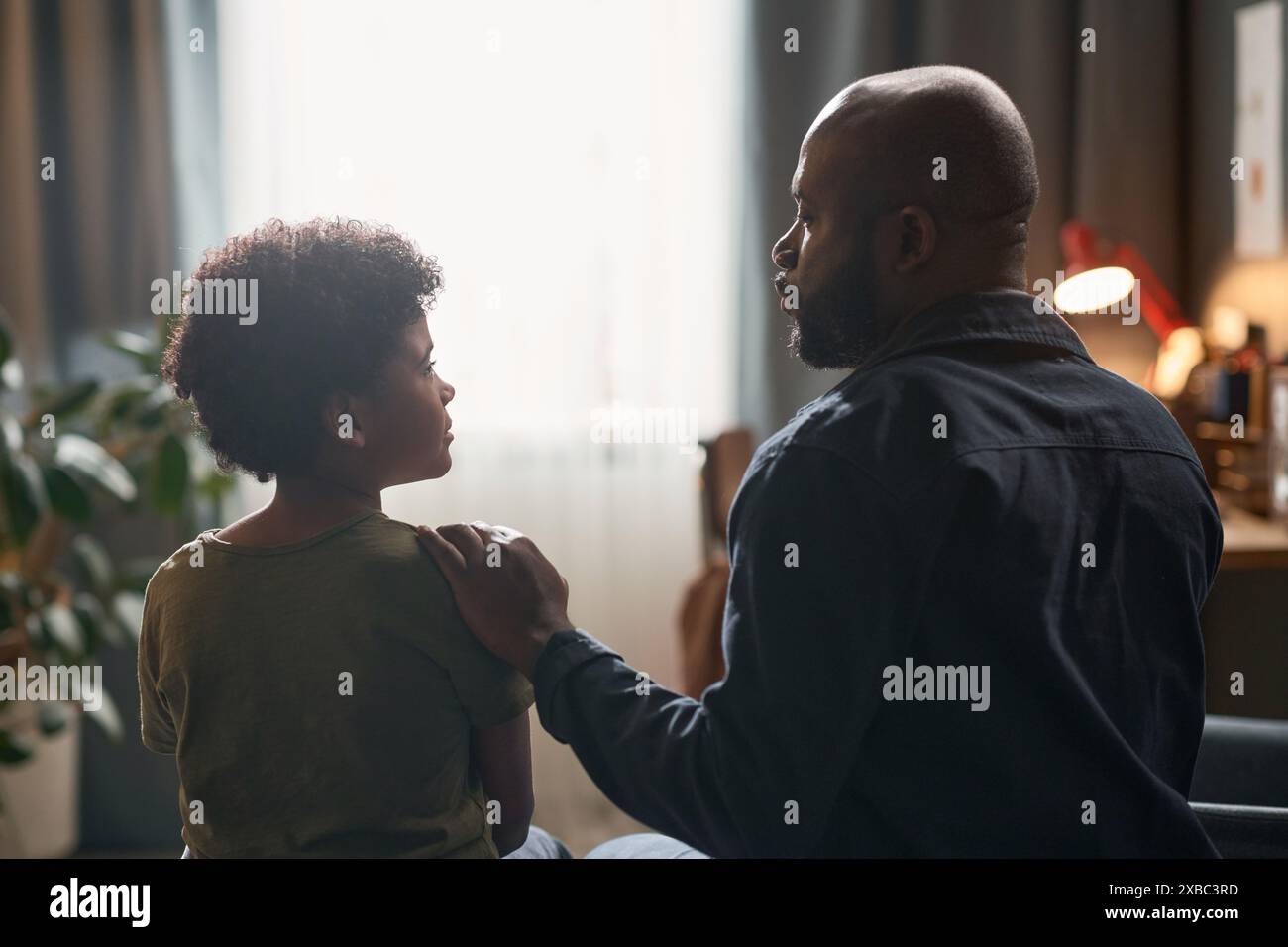 Back view portrait of caring single father comforting young son sitting ...