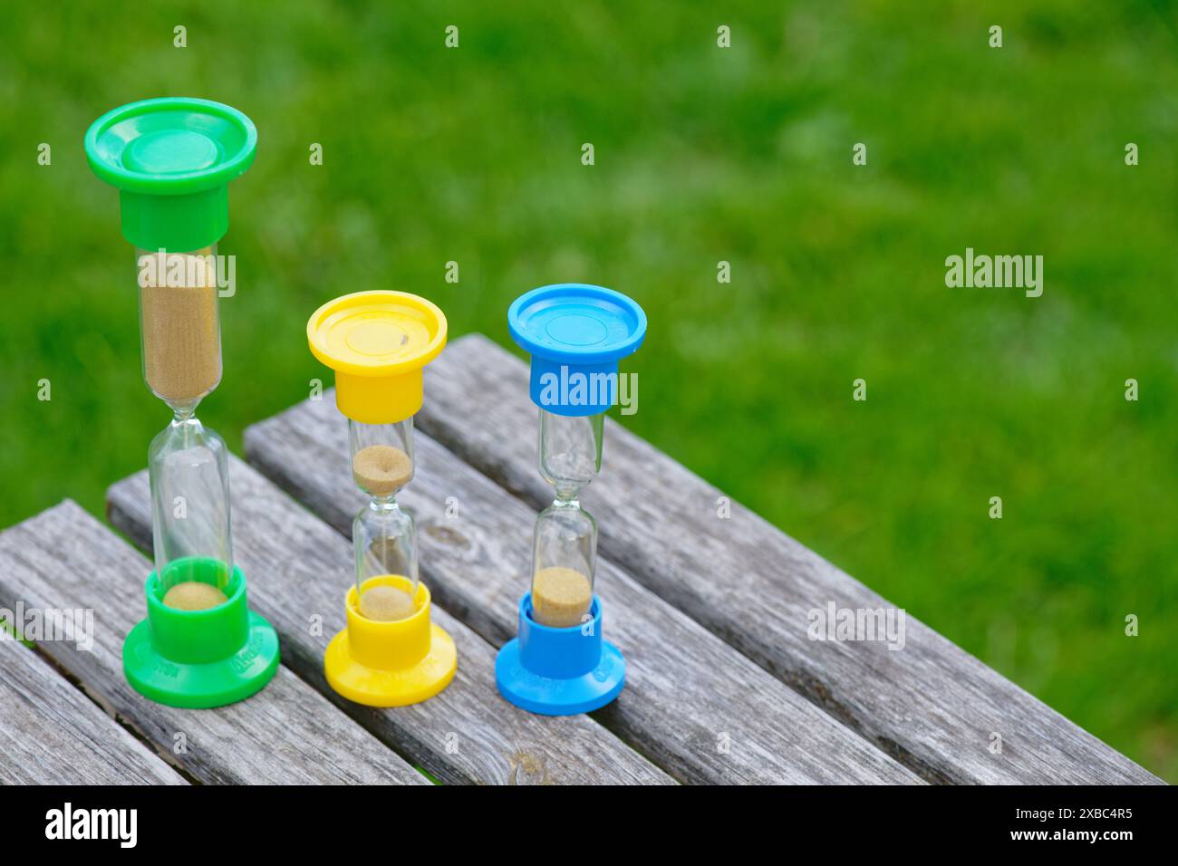 Hourglasses on the green grass natural background Stock Photo - Alamy