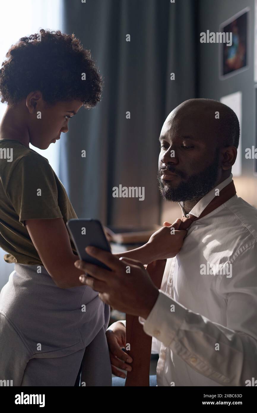 Vertical portrait of young African American boy helping dad getting ...