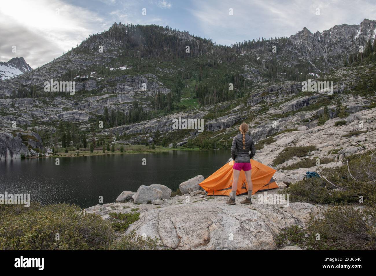 A campsite and tent at the edge of a mountain lake in the mountains of ...
