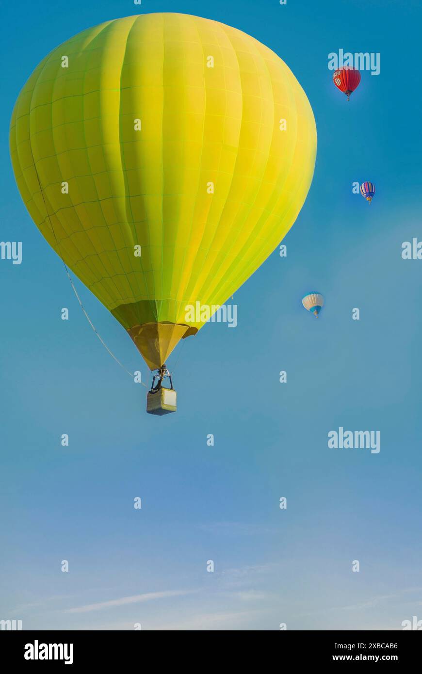 A bright yellow hot air balloon floating in a clear blue sky with ...