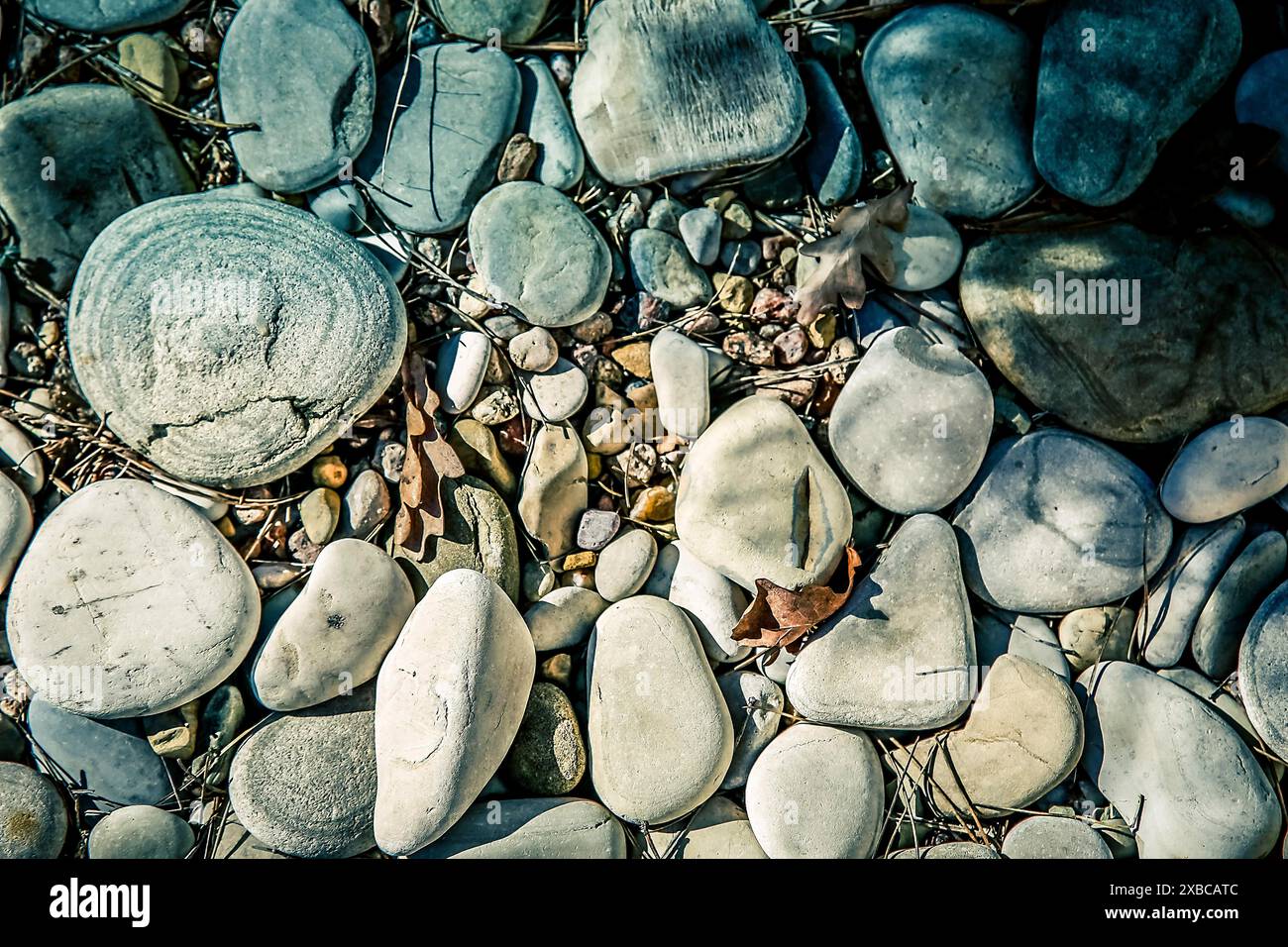 A collection of various sized rocks and pebbles on the ground with ...