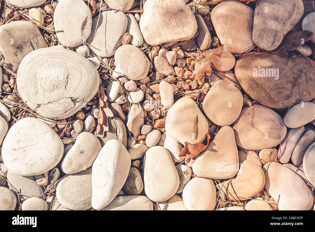 Various sizes of stones and pebbles with a warm sunlight effect and ...