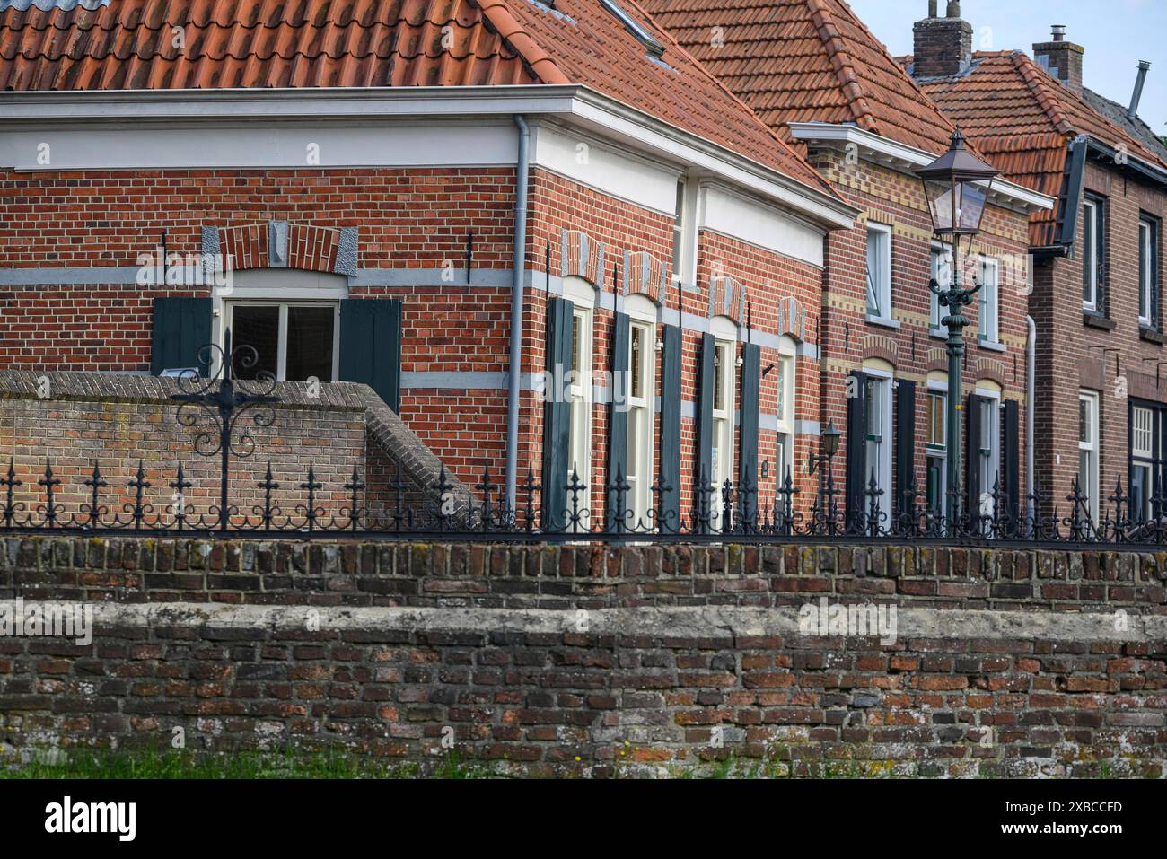 Brick houses with shutters and brick roof, surrounded by a fence ...