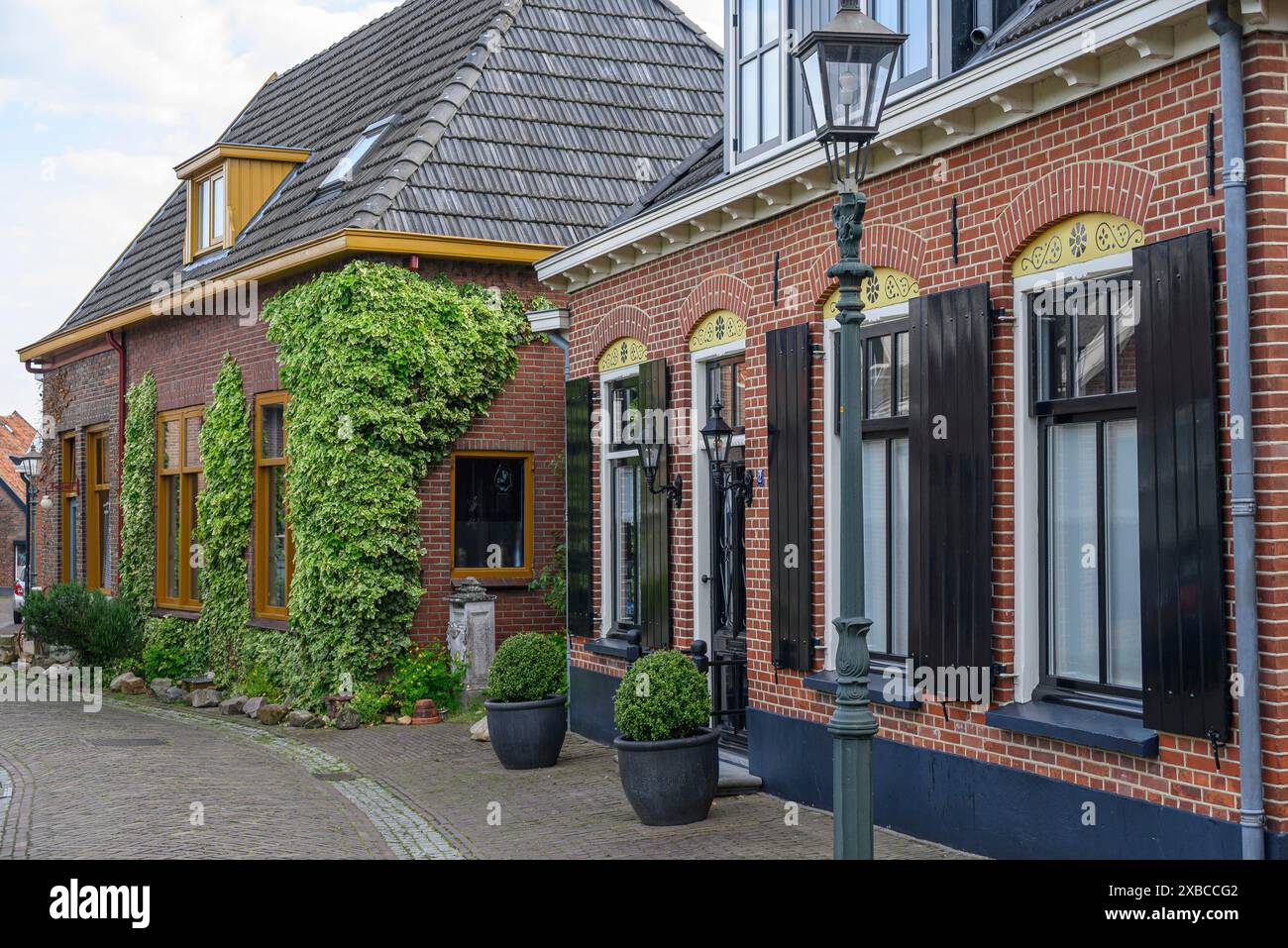 Traditional red brick houses with black shutters and a lantern in front ...