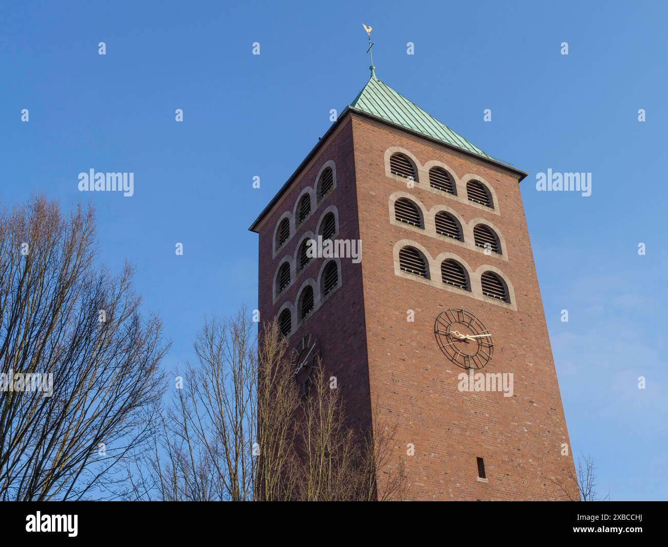 A tall, brick-built tower with a clock and green roof under a clear ...