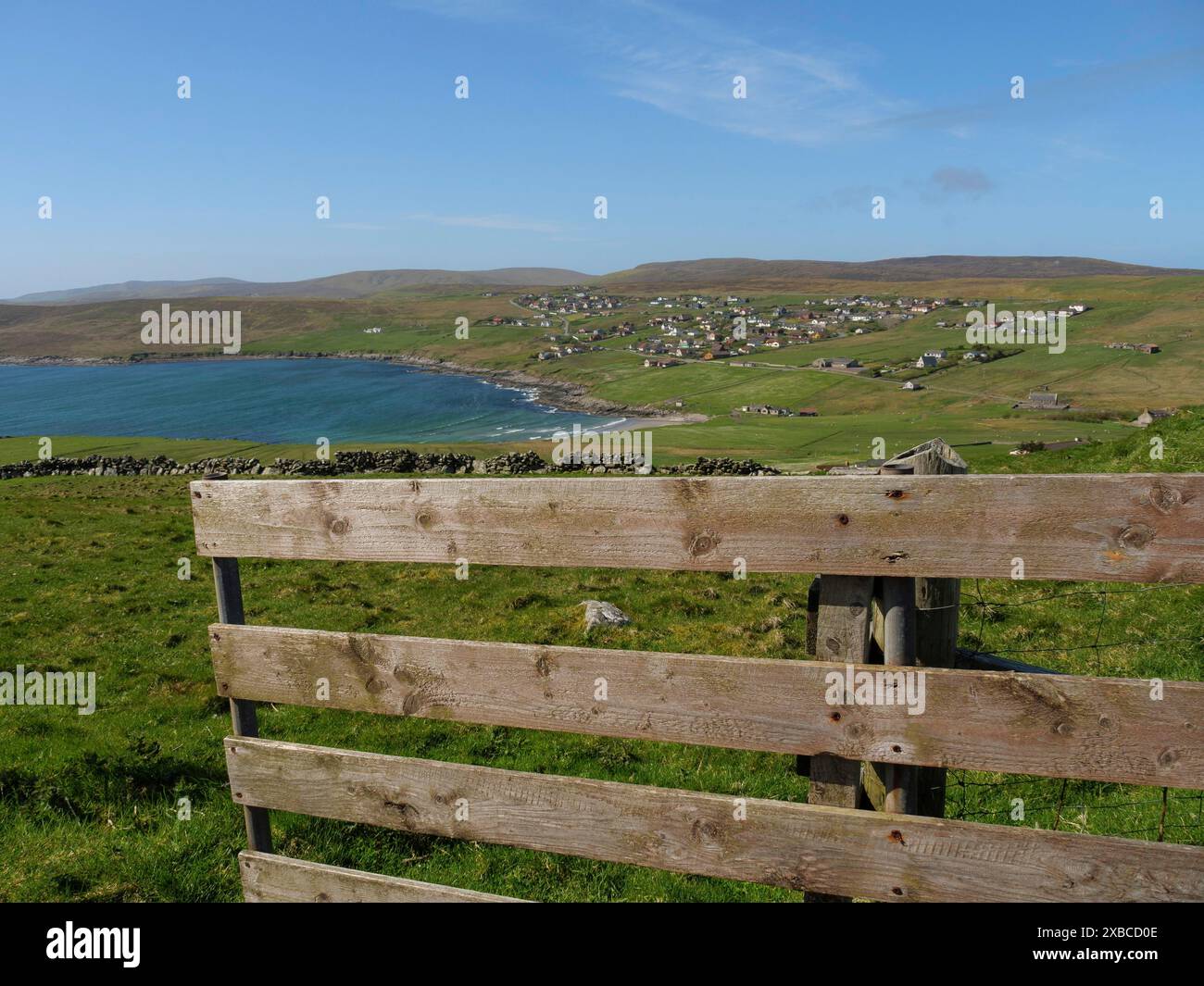 Wooden fence overlooking a coastline and a village surrounded by green ...