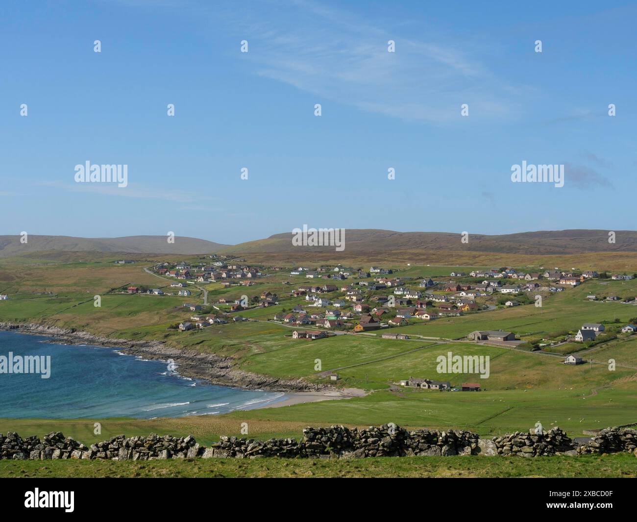 A coastal village scene with green fields and scattered houses under a ...