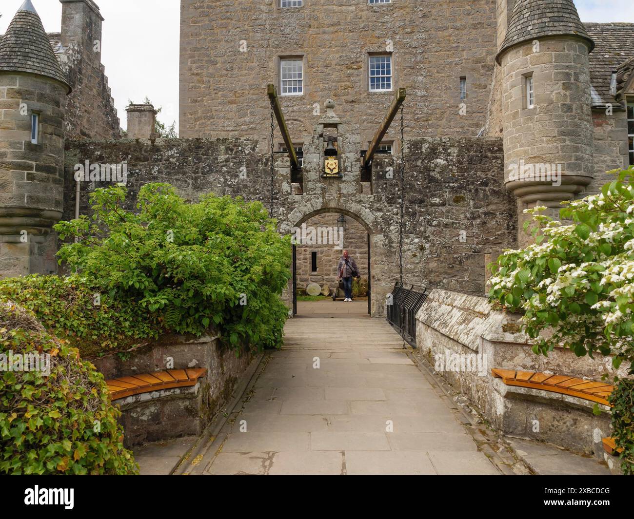 A historic entrance with Tor tor to a castle, flanked by stone walls ...