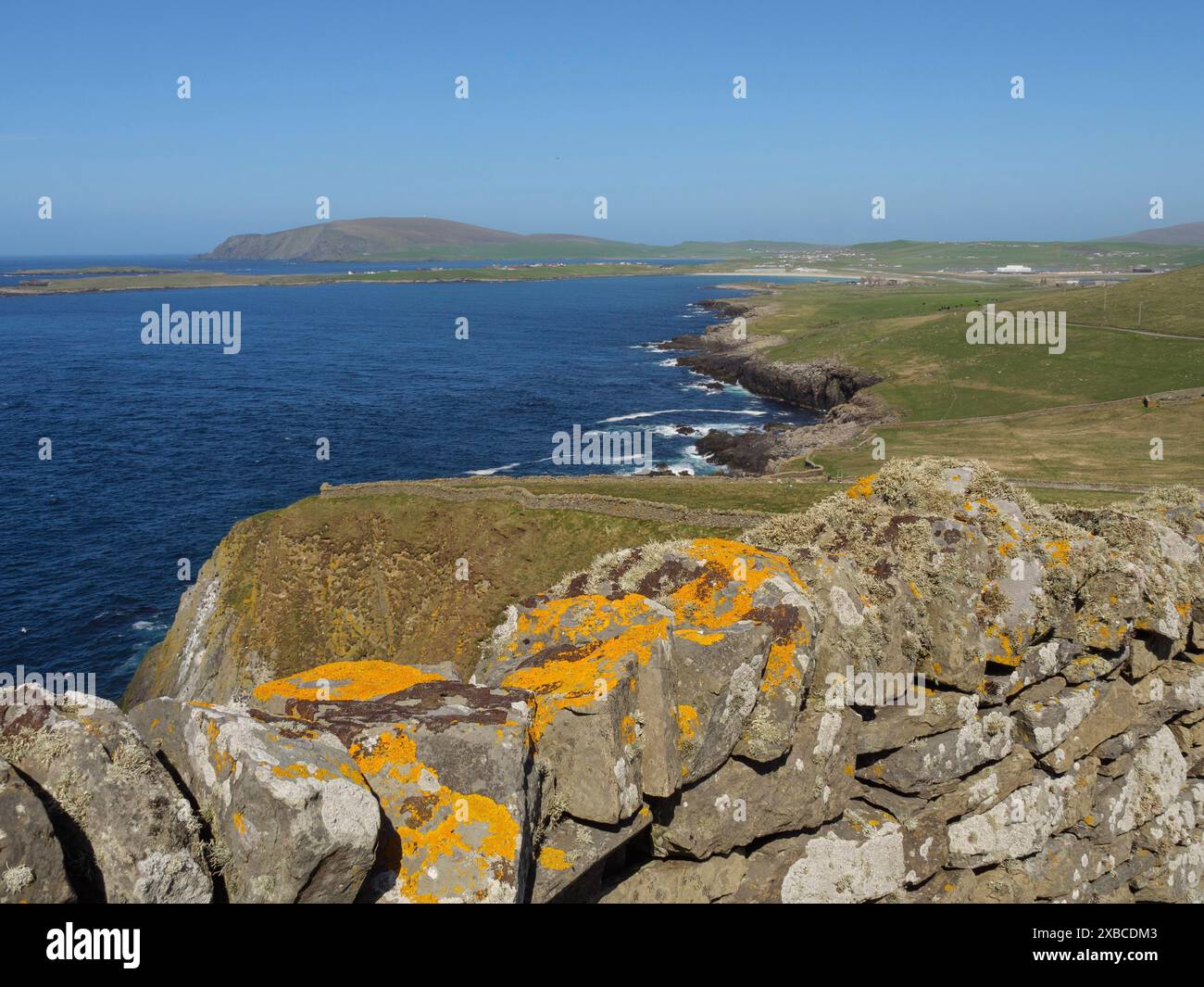 Stone wall with seaweed in the foreground, behind it sea and green ...