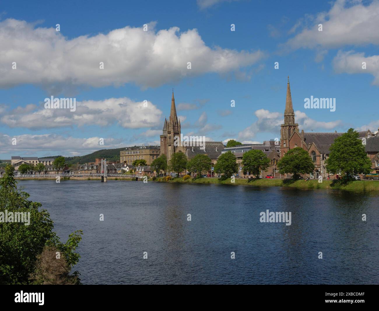 Two church steeples and urban buildings on the banks of a river under a ...