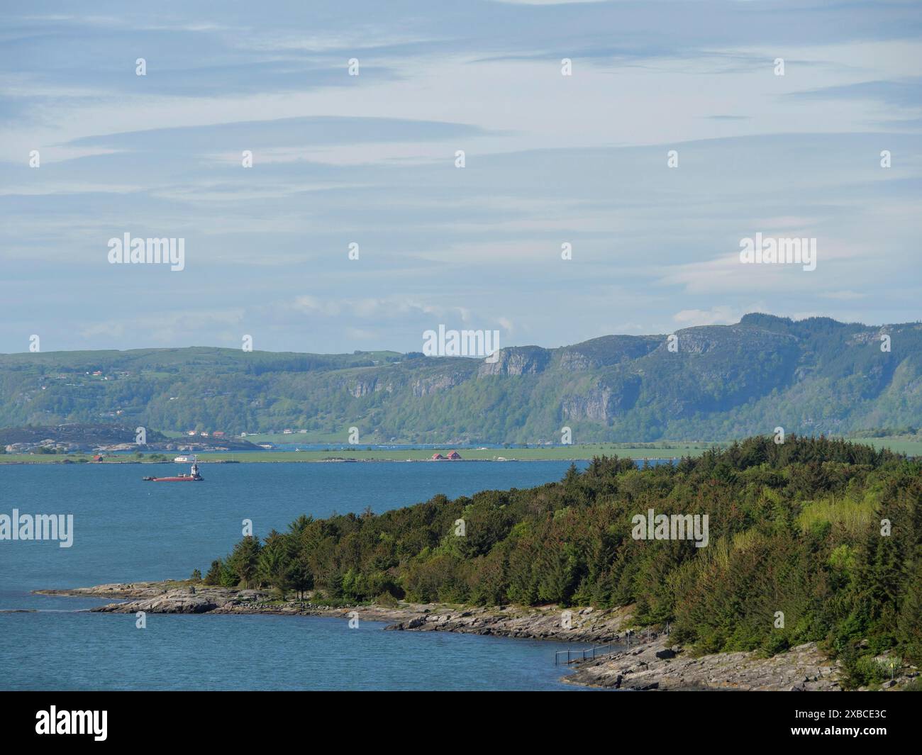 A wide coastal landscape with green vegetation and mountain background ...