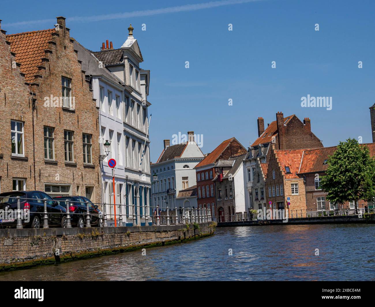 Rows of historic buildings along a canal with passing cars under a blue ...