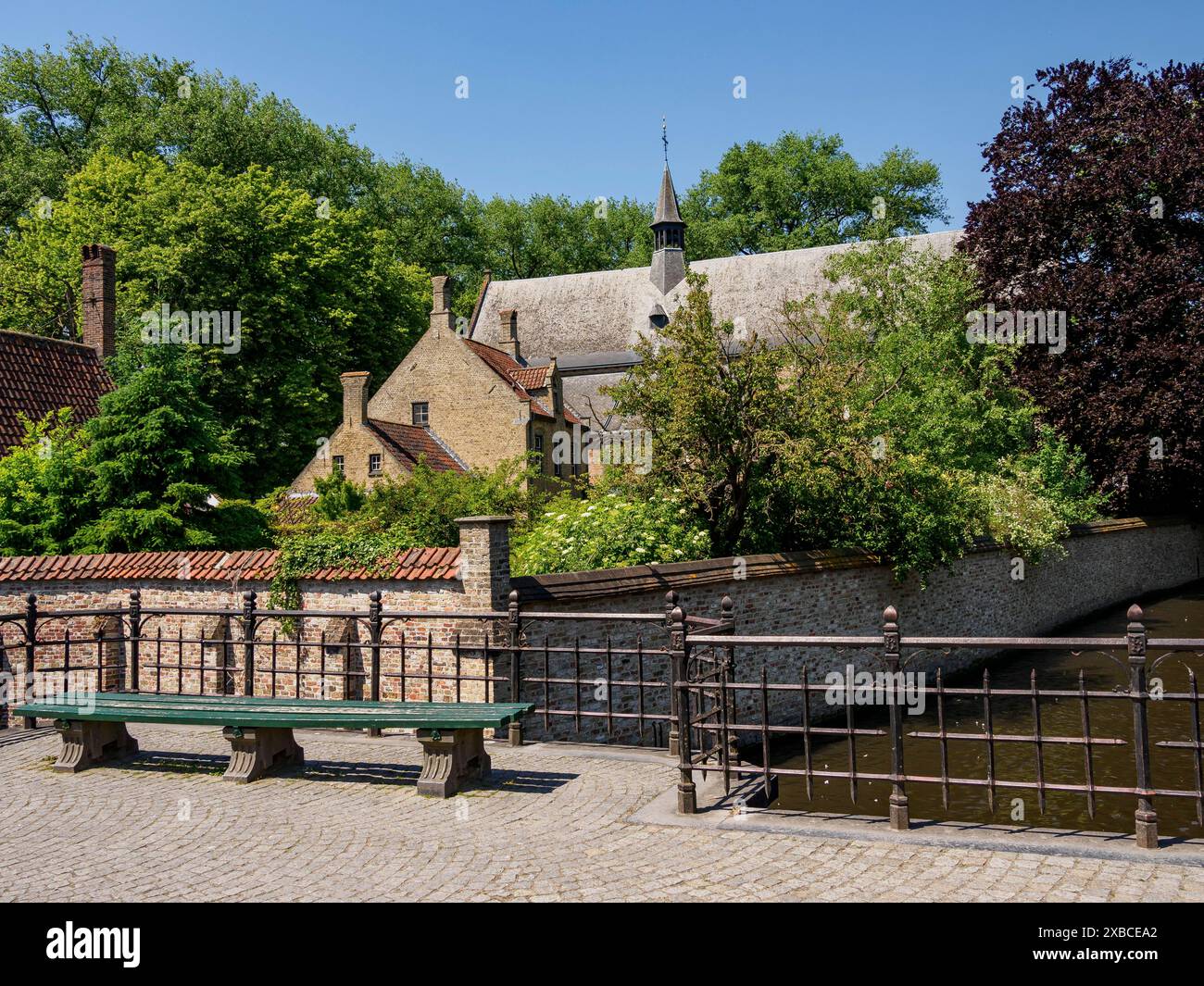 Park bench on stone pavement in front of a historic church and a river ...