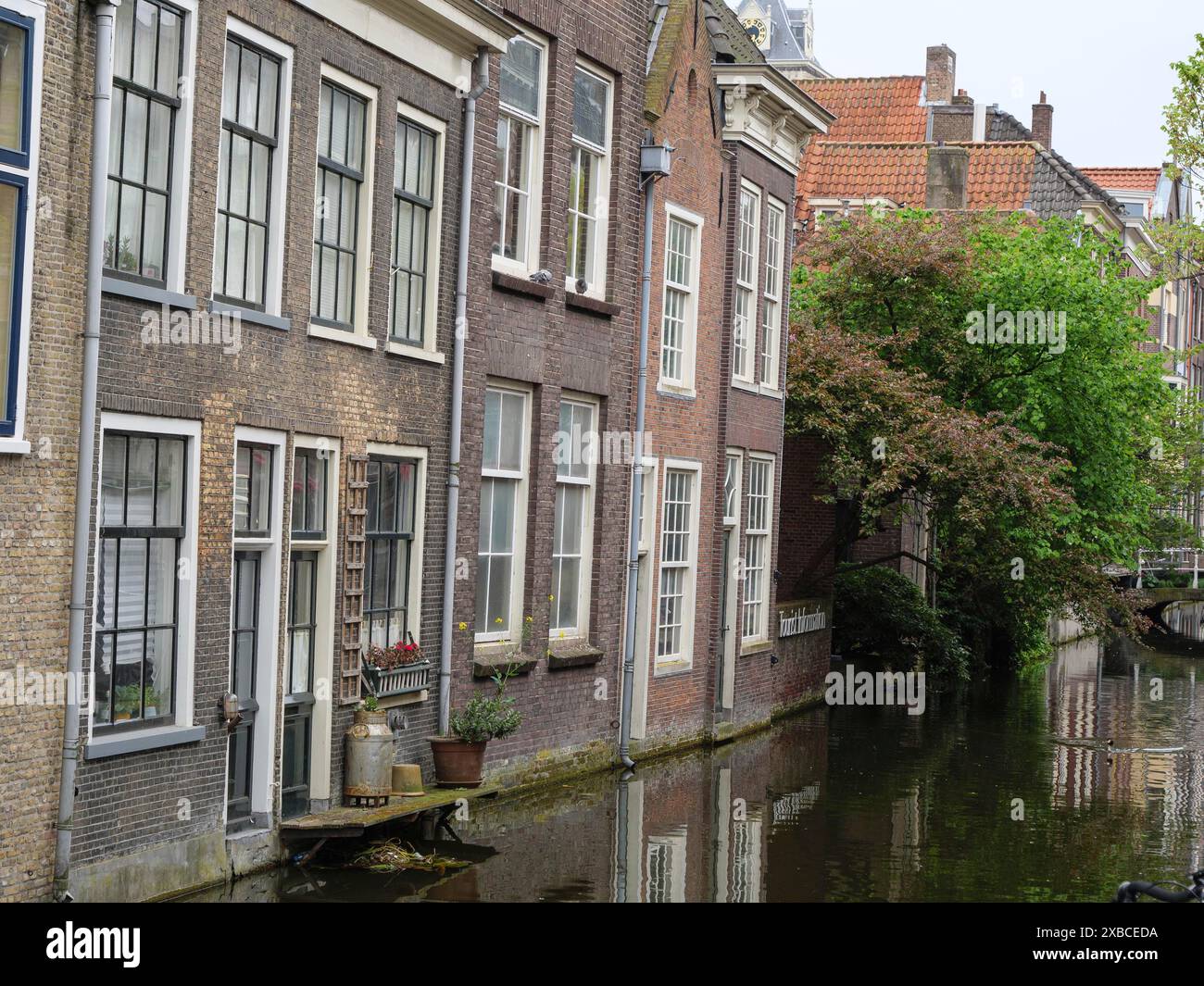 Historic brick houses on the canal with green plants and reflections in ...