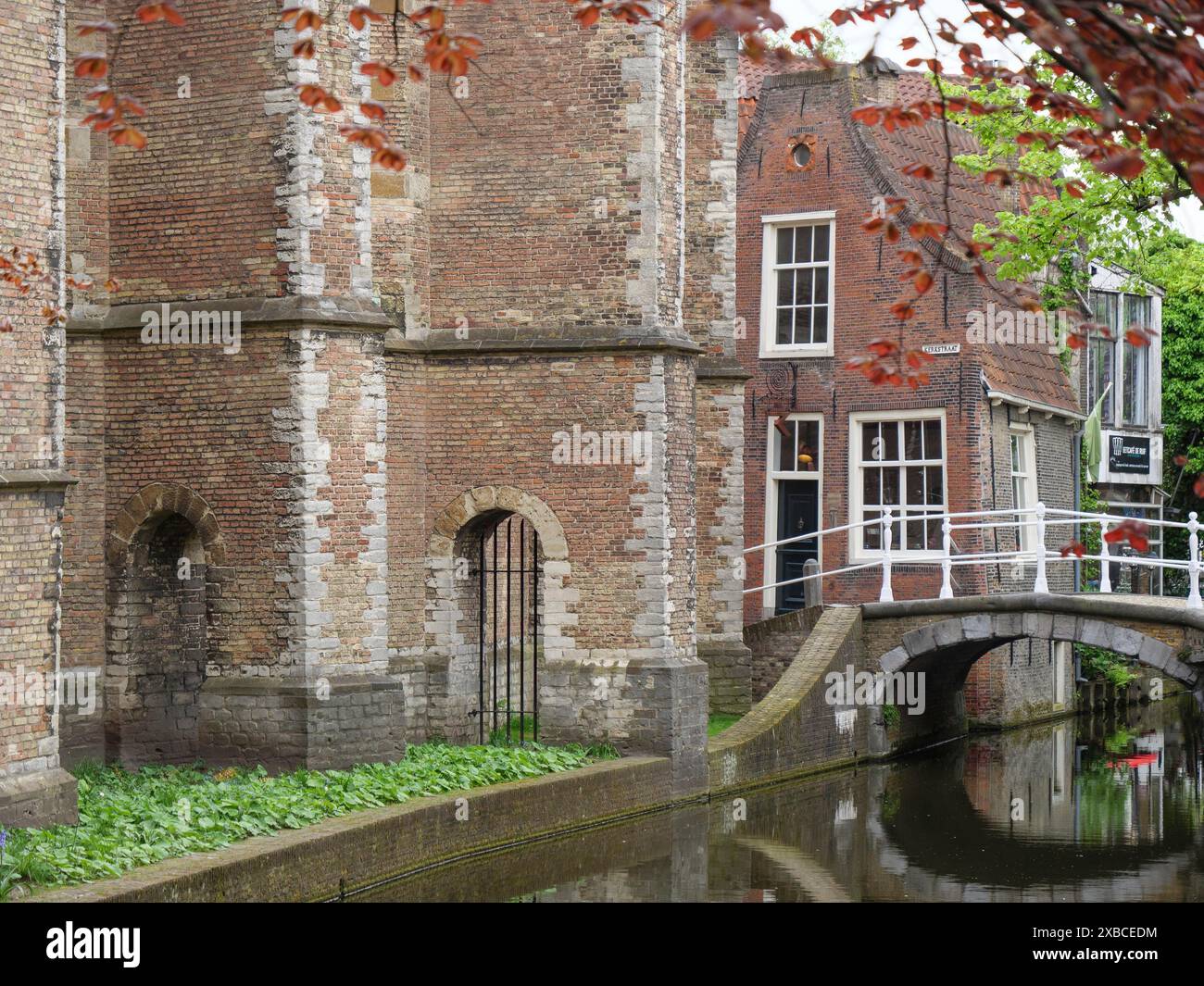 Brick wall of a historic building on a canal with bridge, red foliage ...