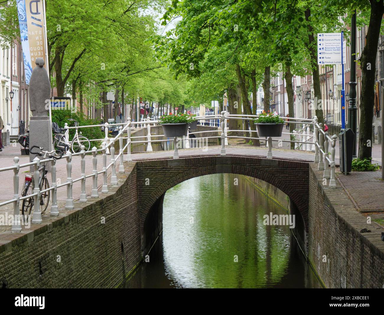 Small bridge over a canal surrounded by trees and flower pots in a ...