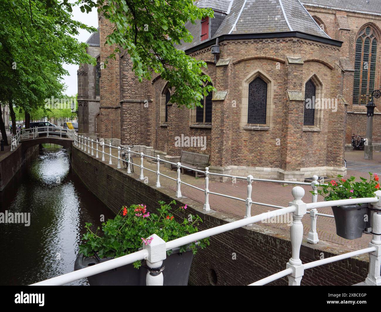Church building next to a canal with flower pots and trees, Delft ...