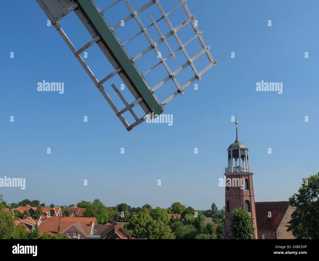 Parts of a windmill and a church tower rise above the roofs of a quiet ...