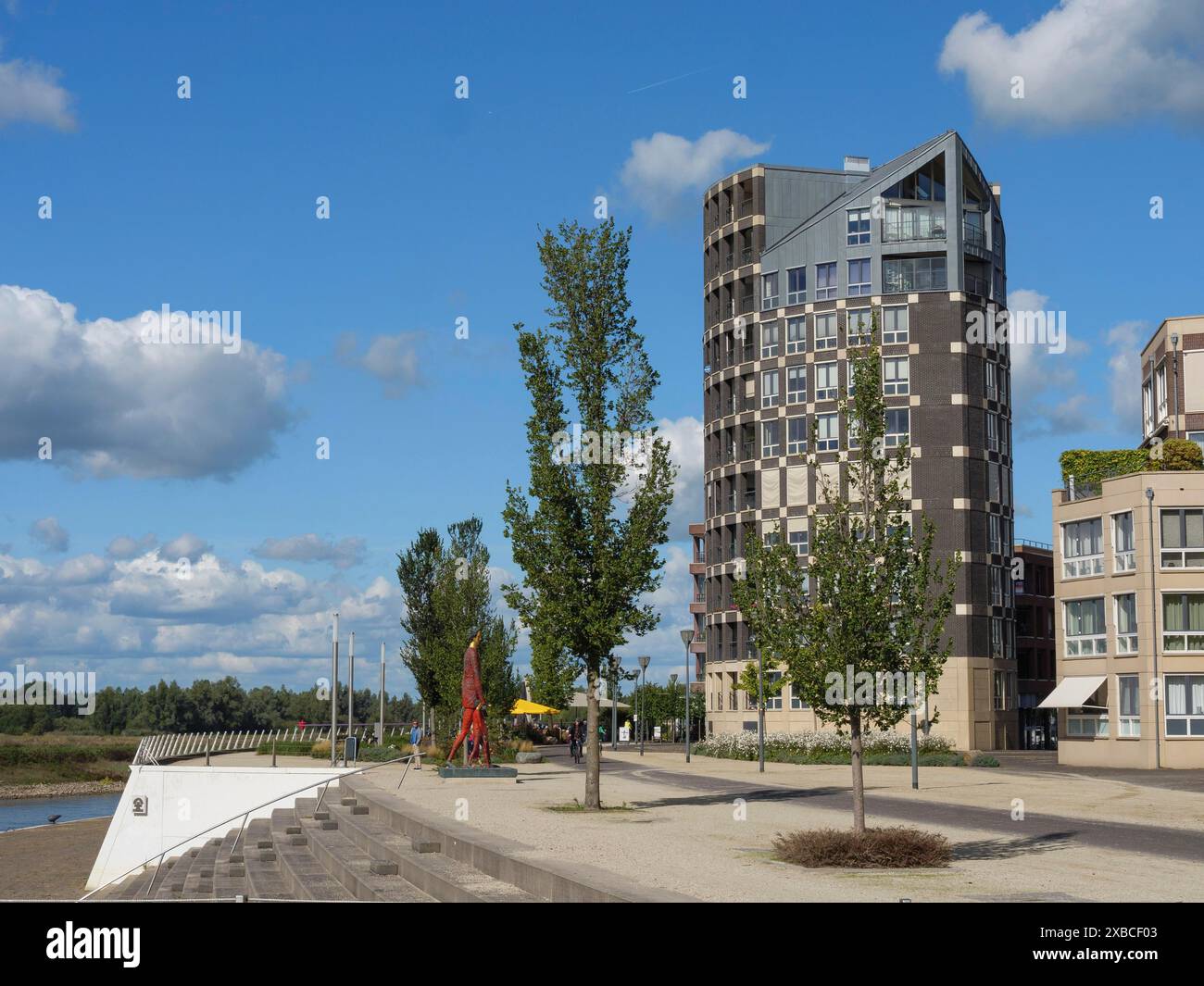 Modern residential complexes on a riverbank with trees and walking ...