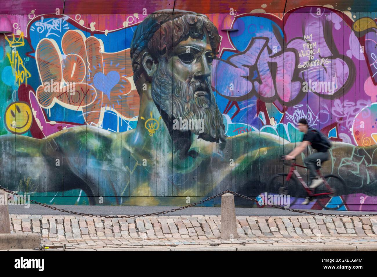 God of Greek mythology, Zeus, large graffiti on building fence, cyclist ...