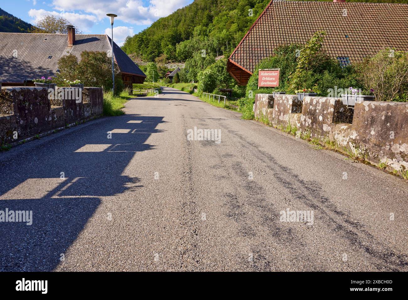 Old bridge with stone walls, flower boxes, road and Black Forest houses ...