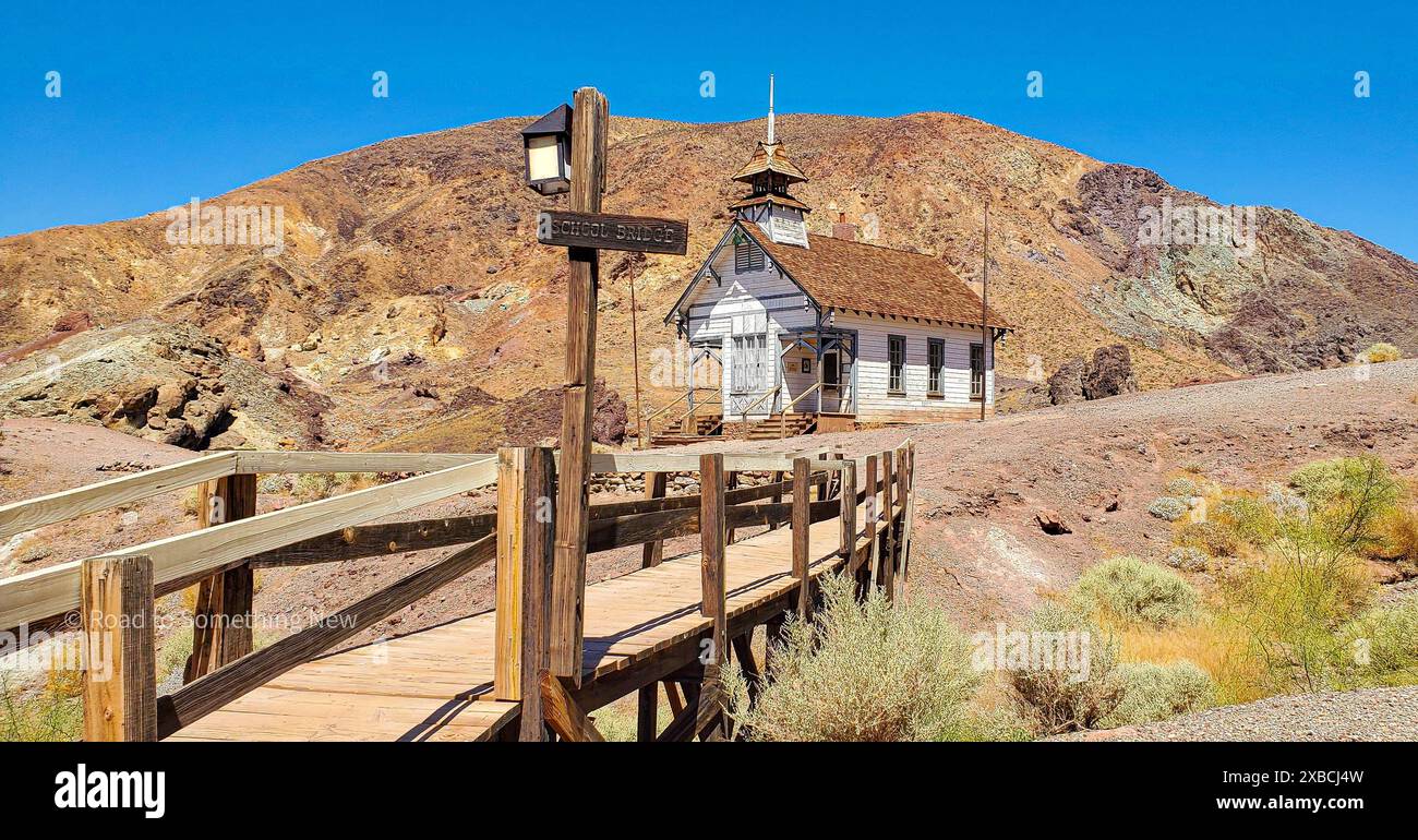 A historic schoolhouse in the desert with a wooden bridge leading to it ...