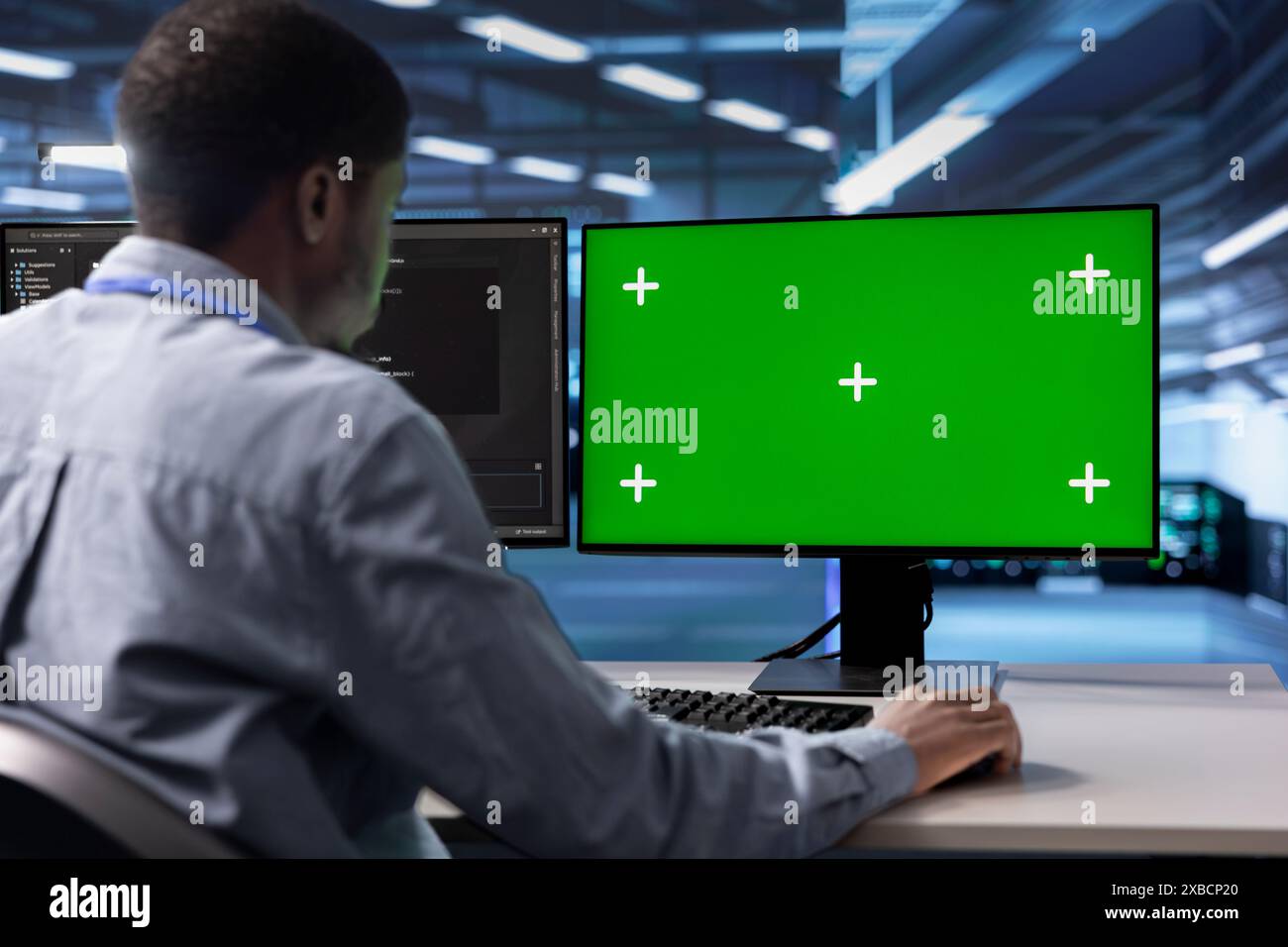 African american man in data center using green screen computer to check for server performance ...