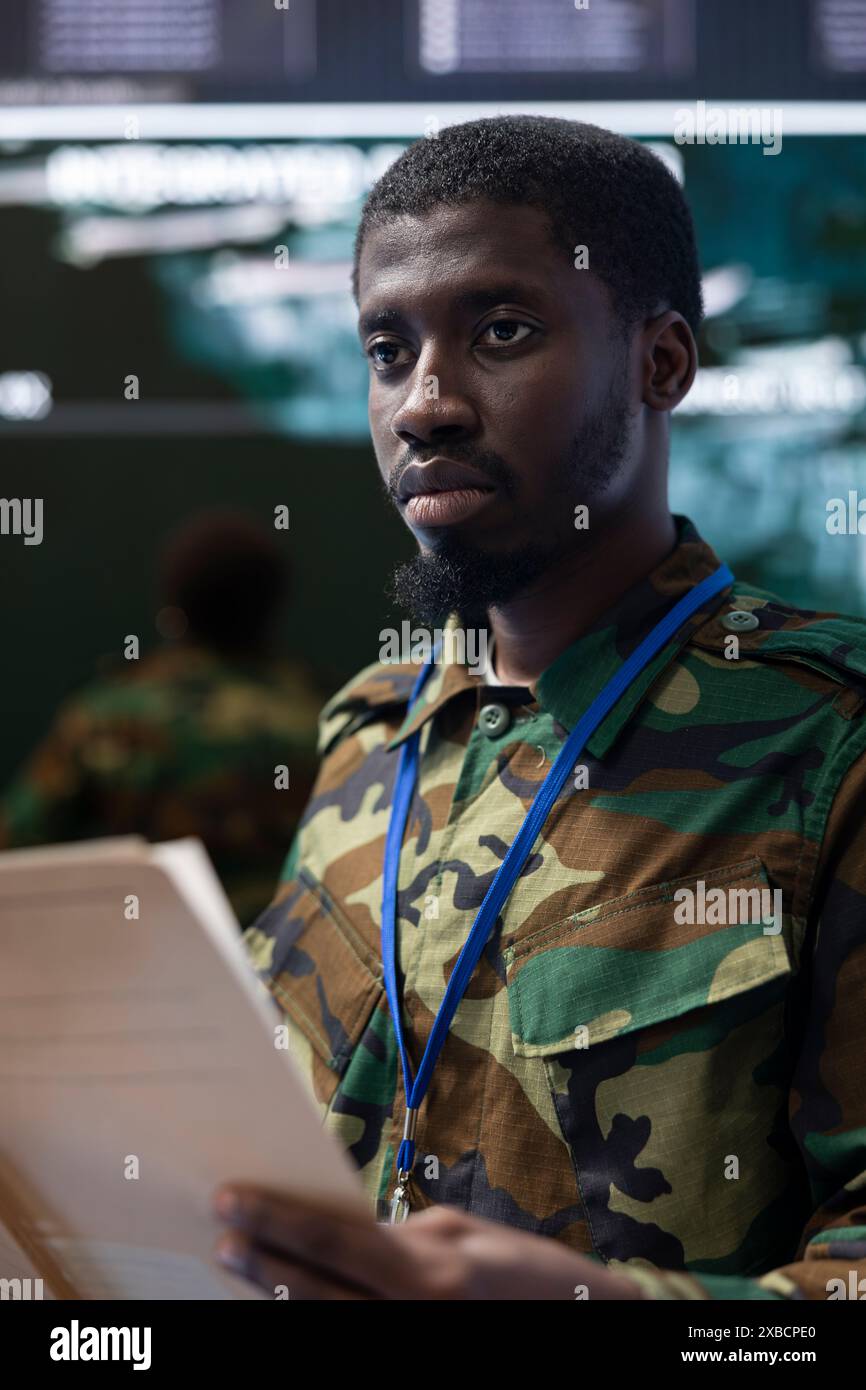 Army soldier reading a new defense mission case file in federal headquarters, using ...