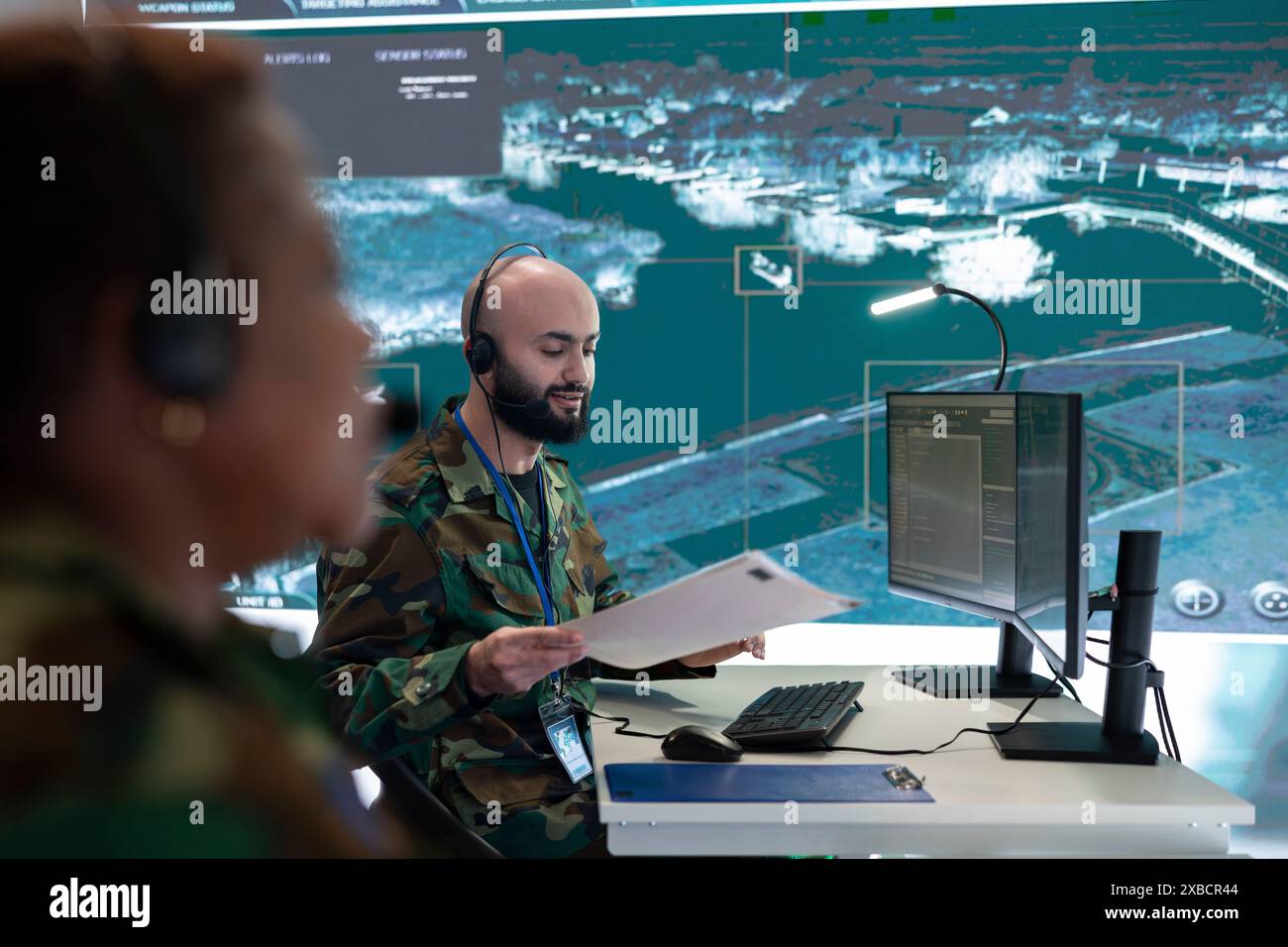 Skilled IT engineer monitoring satellite CCTV footage recorded on computer and big screen in ...