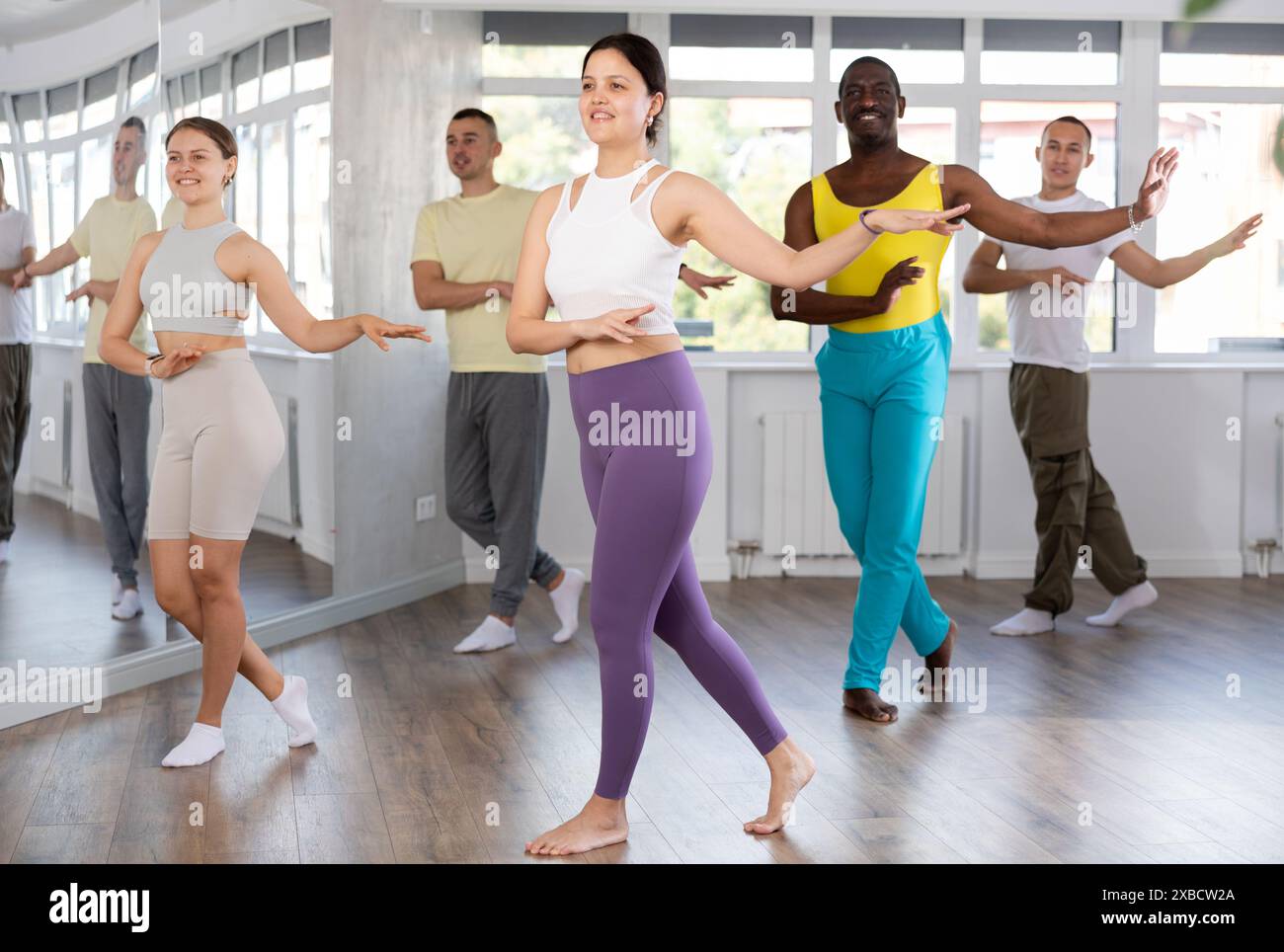 Group of multinational sports people rehearsing social dance in dance ...
