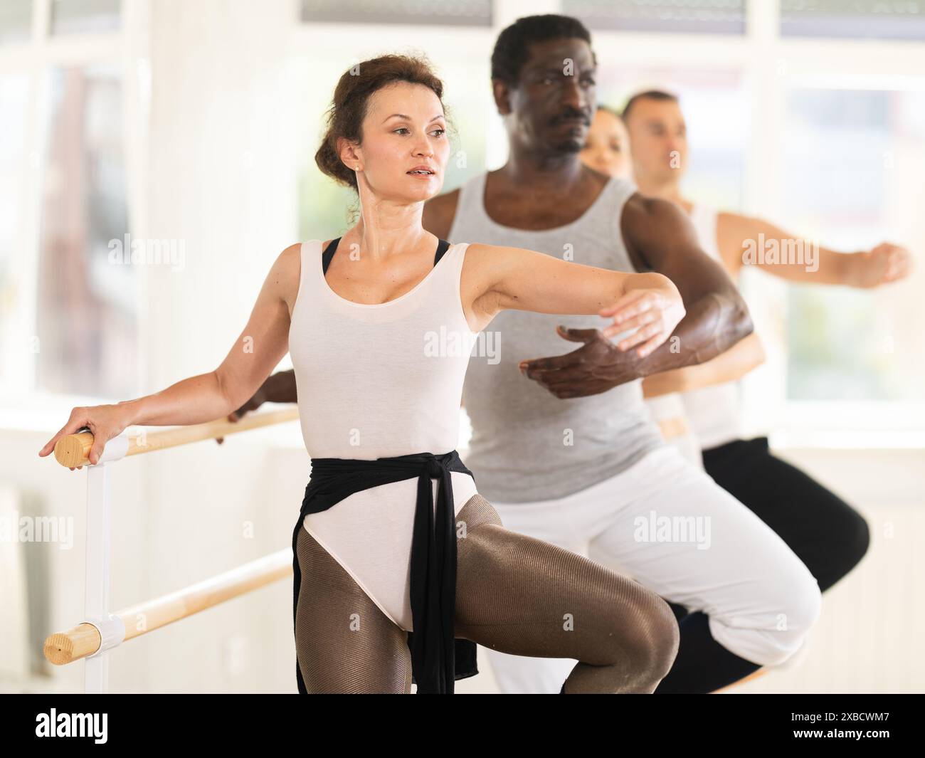Group of dancers practicing develope at barre Stock Photo - Alamy