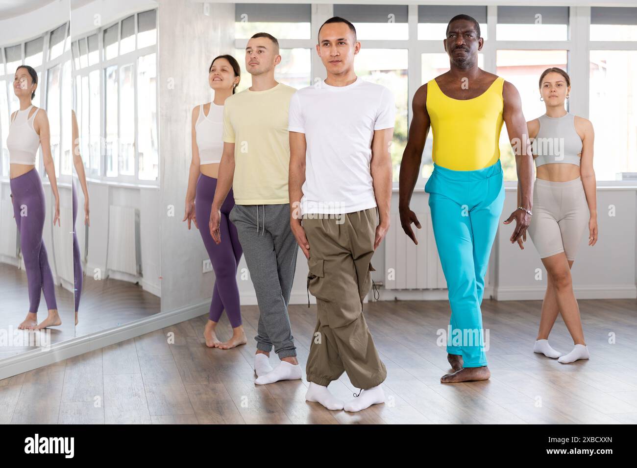 Positive young multinational people forming line while rehearsing ...