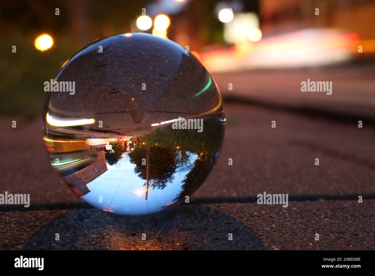 Beautiful city street, overturned reflection. Crystal ball on asphalt ...