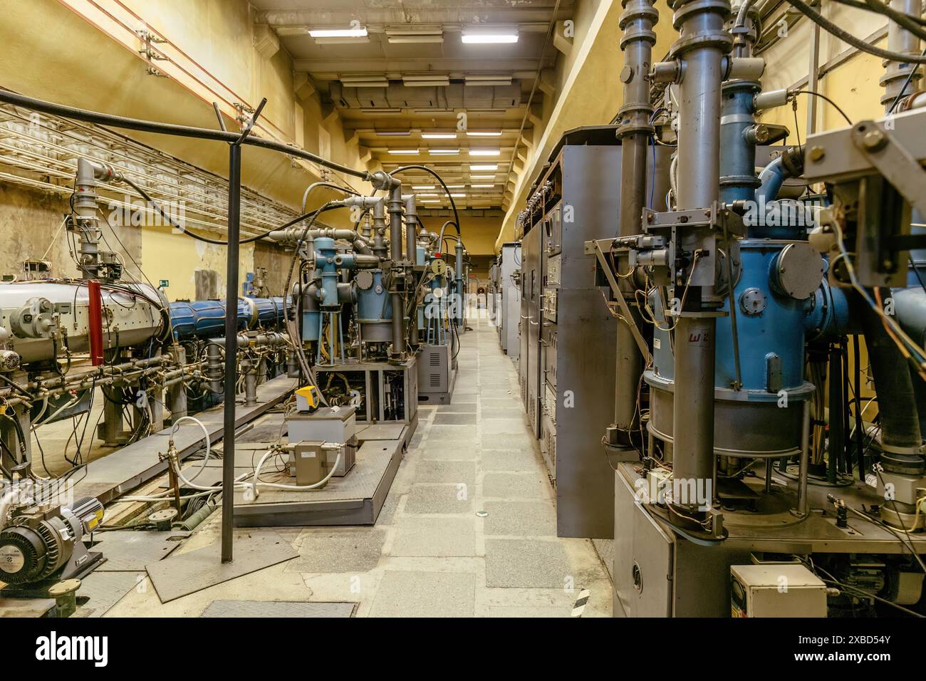 Old experimental equipment with large metal tube and pumps in workshop ...
