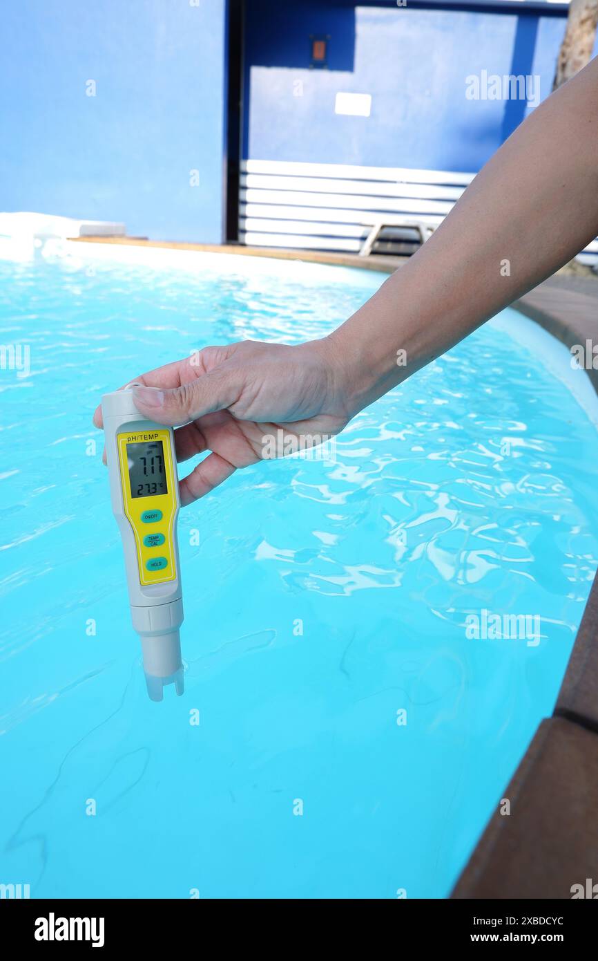 Digital water testing in female hand on swimming pool background, ph ...