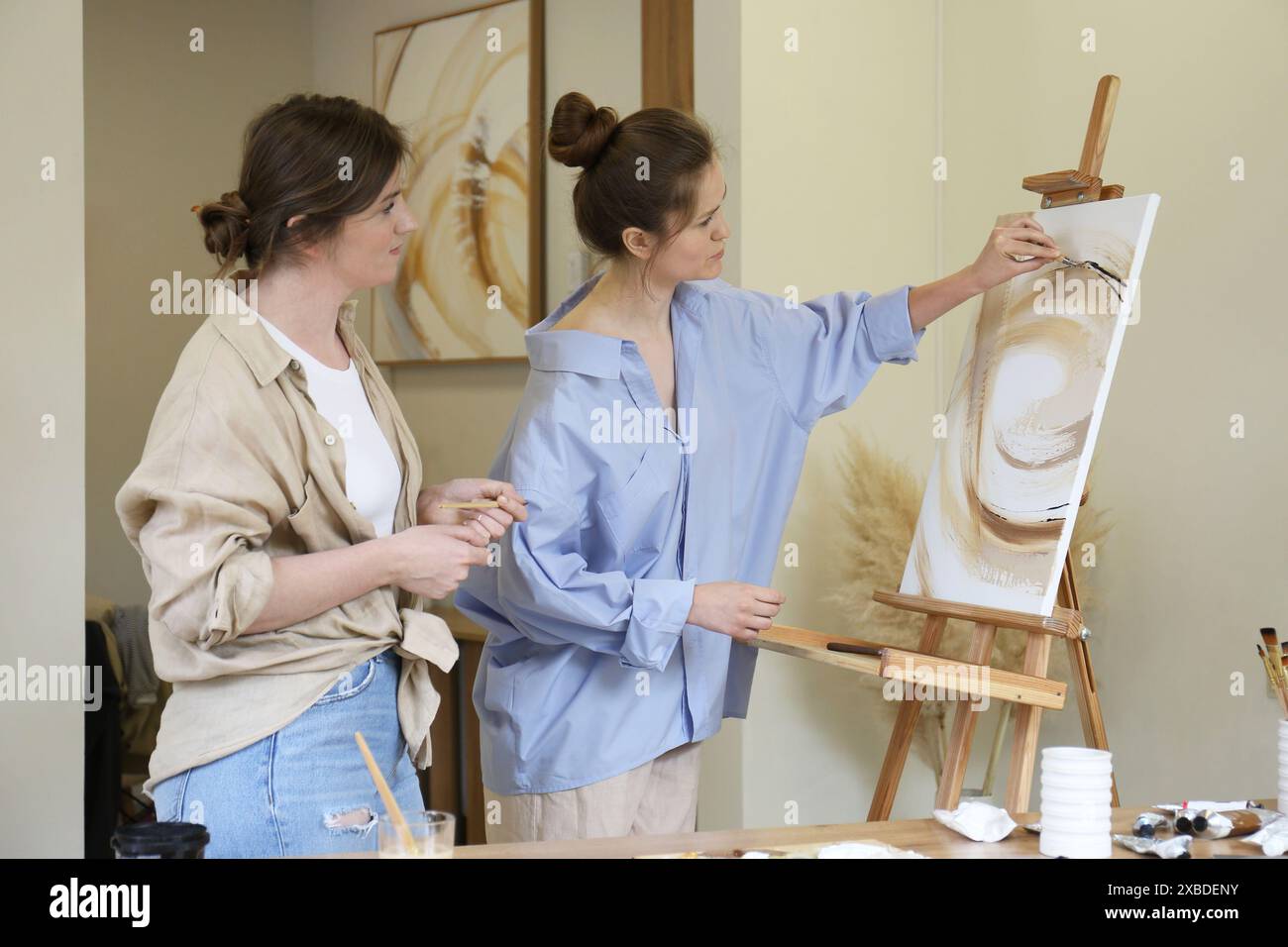 Artist teaching her student to paint in studio Stock Photo - Alamy
