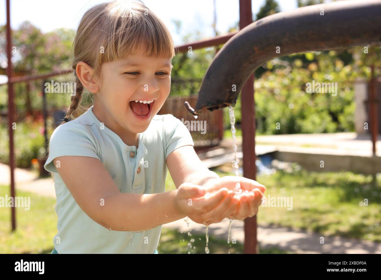 Water scarcity. Cute little girl drawing water with hands from tap ...