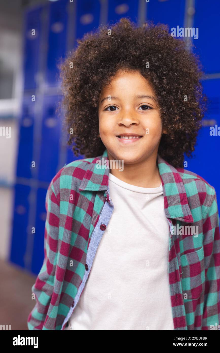 Biracial student smiling in front of blue background school lockers ...