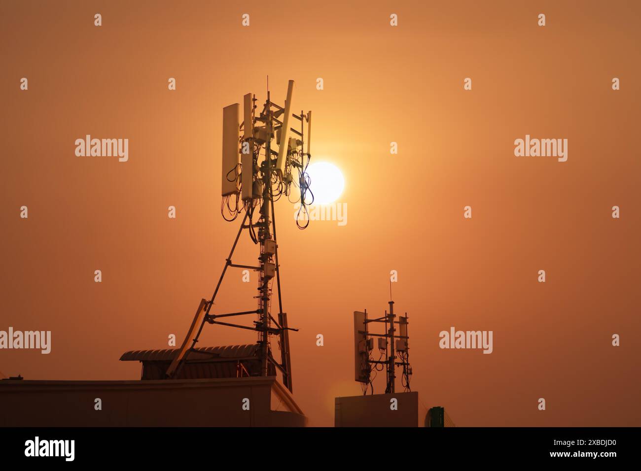 Two antennas on a rooftop beside the sun Stock Photo - Alamy