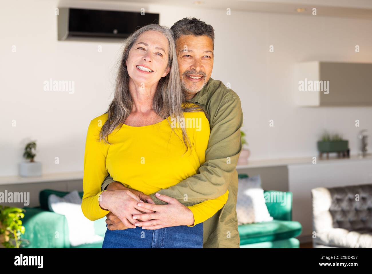 A mature biracial mature couple embracing and smiling warmly at home ...