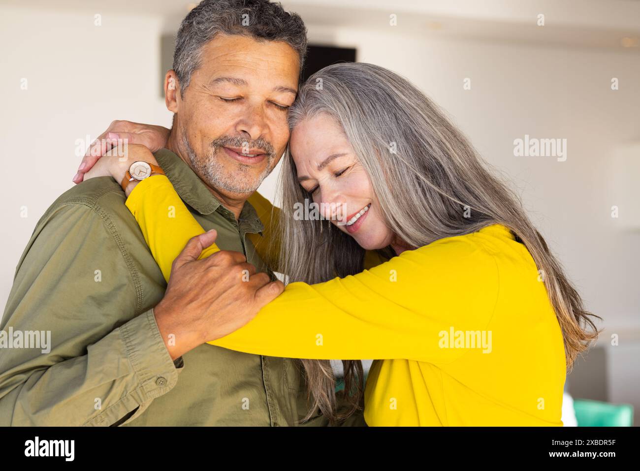 Biracial mature couple embracing and smiling warmly at home, at home ...