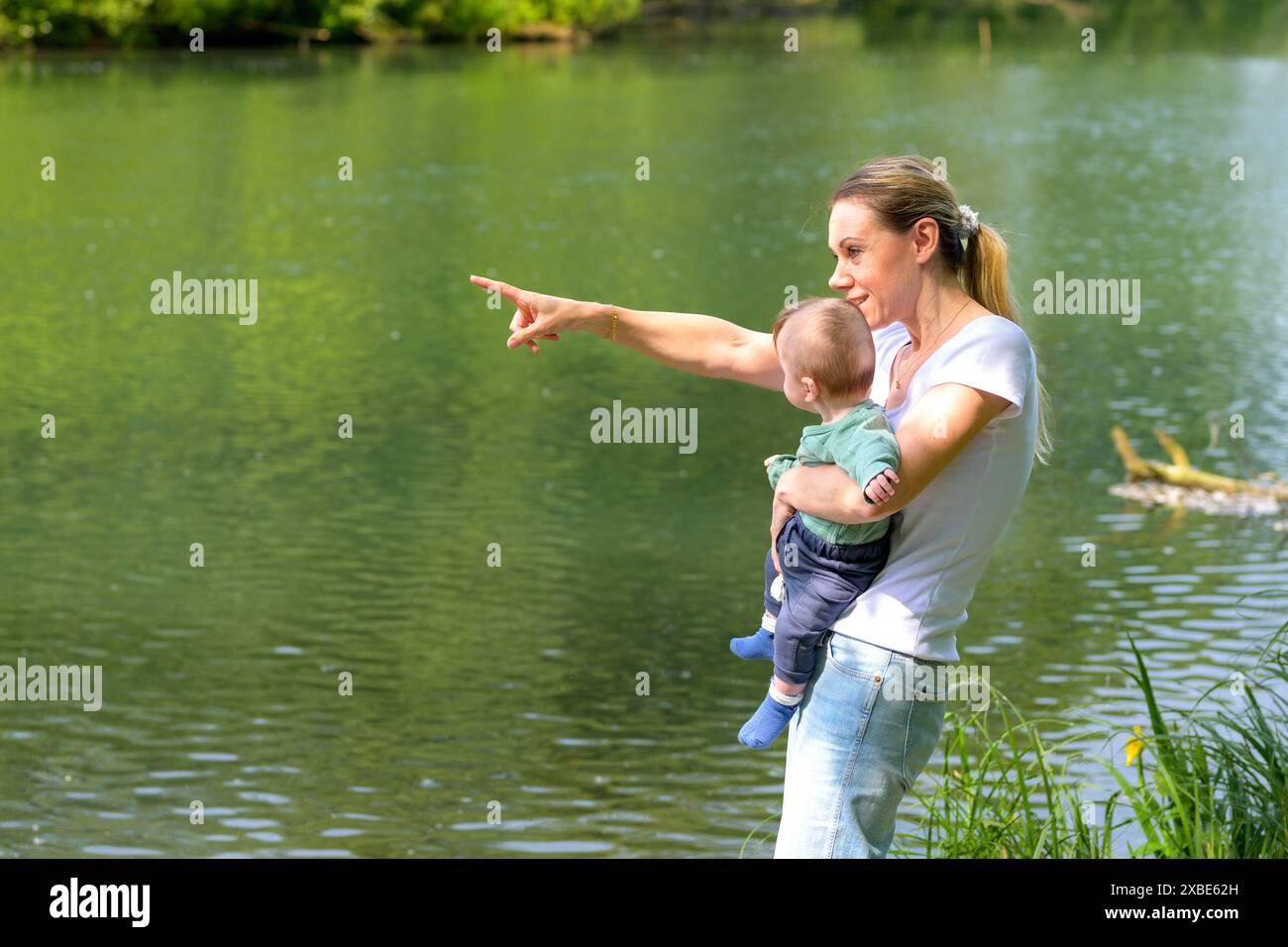 A mother, holding her baby, points towards something in the distance by ...