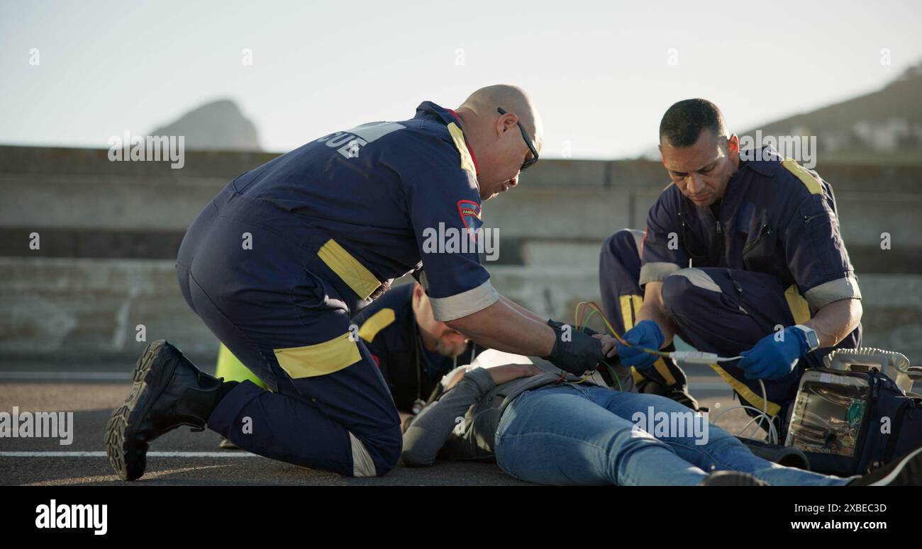 Paramedic, rescue and team with patient, outdoor and EKG to check heart ...