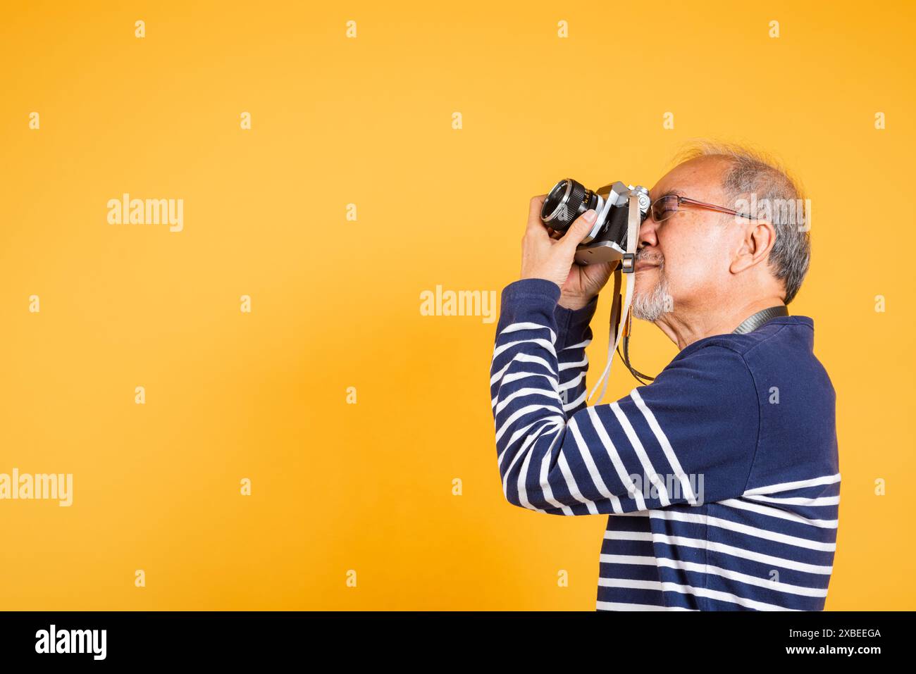 Portrait Asian old man wearing glasses look viewfinder vintage SLR camera studio shot isolated ...