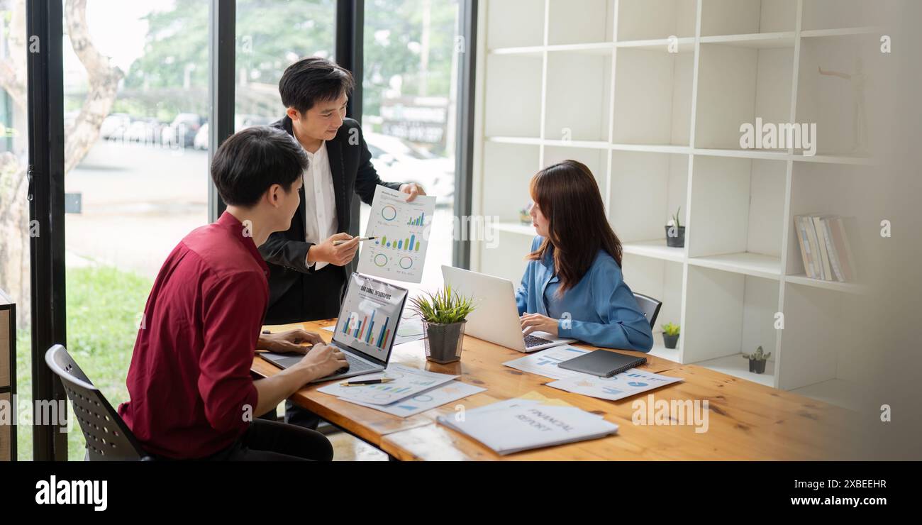 Business Team Discuss Analysis in Modern Office Setting with Charts and Laptops, Collaboration ...