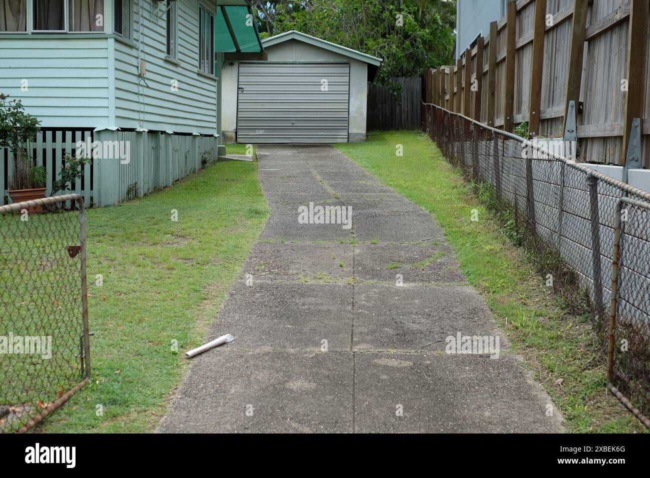 Concrete driveway running beside a weatherboard suburban house to a ...