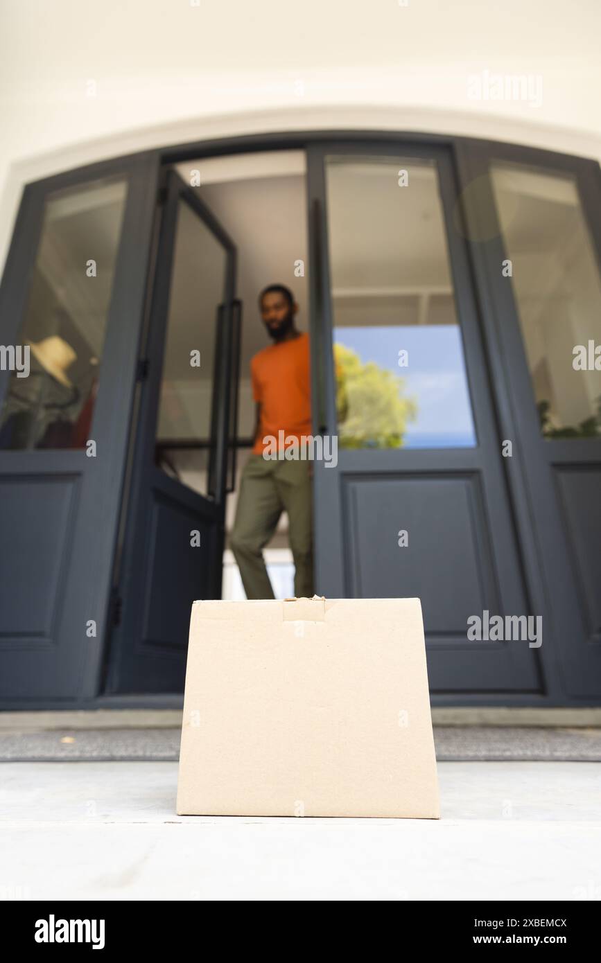 African American young man standing at front door looking at package on ...