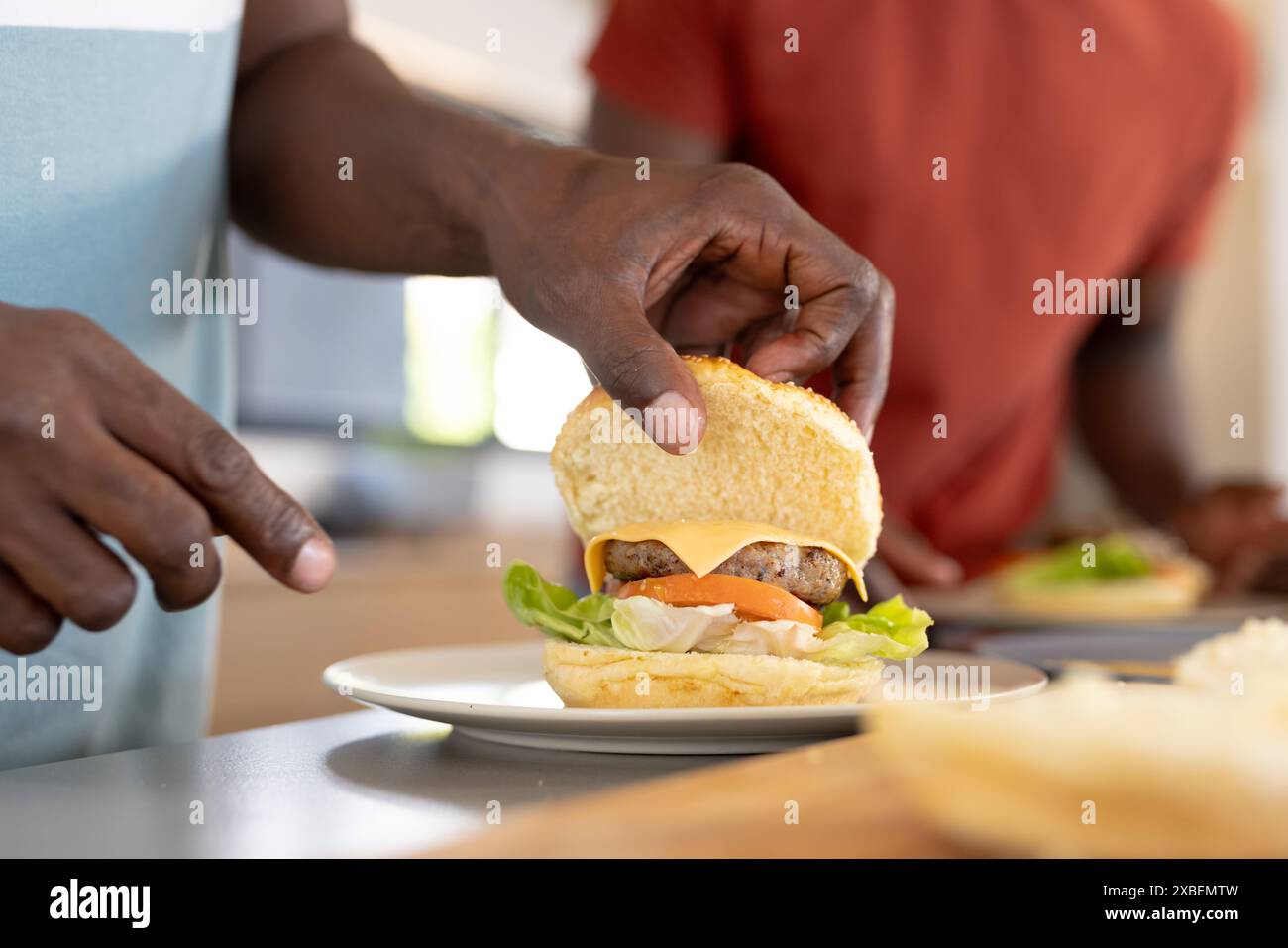 African American father and son preparing cheeseburger together in ...