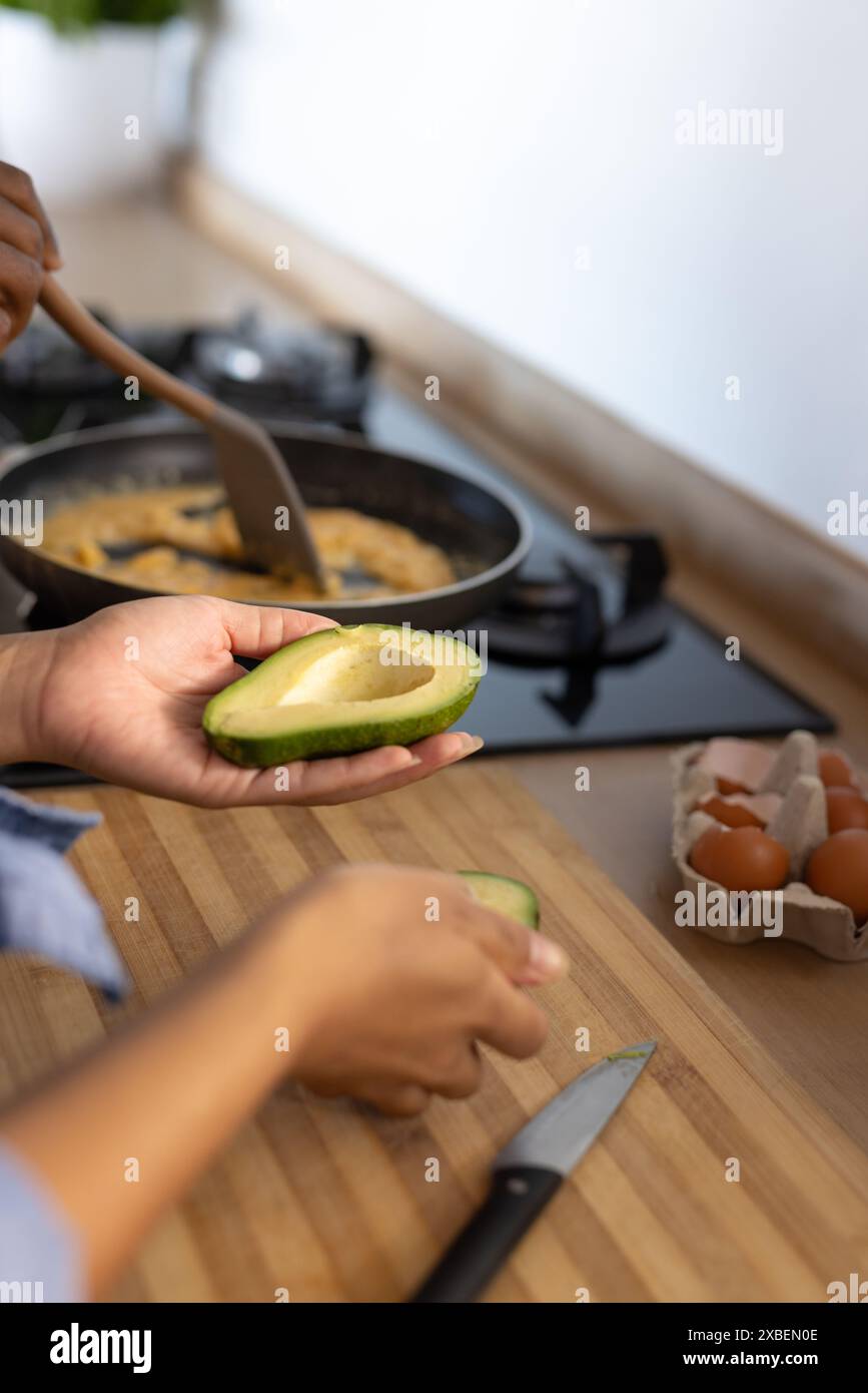 Young diverse couple preparing breakfast with avocados together in ...